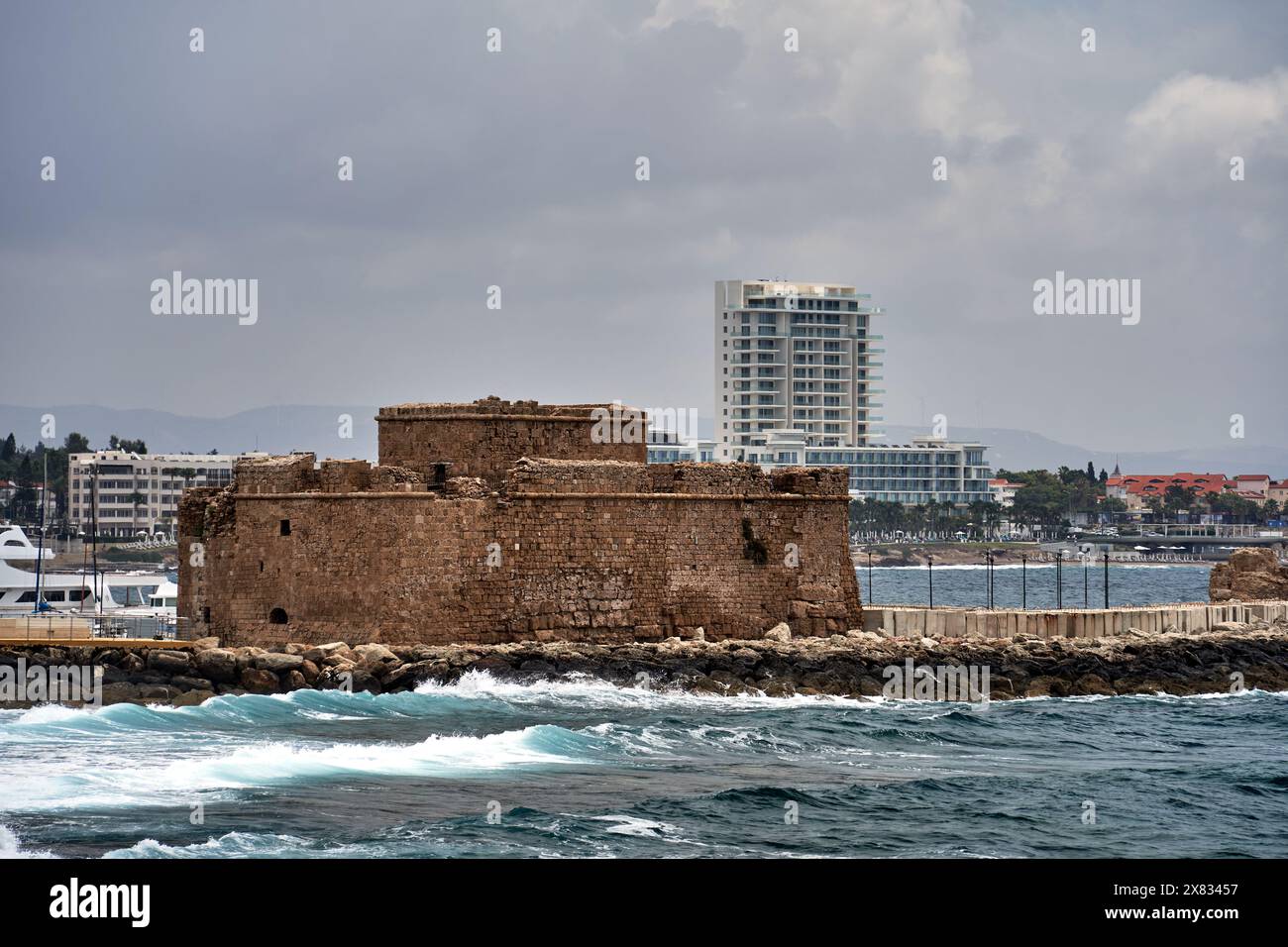 Ruins of a medieval stone castle and modern buildings in the port of ...