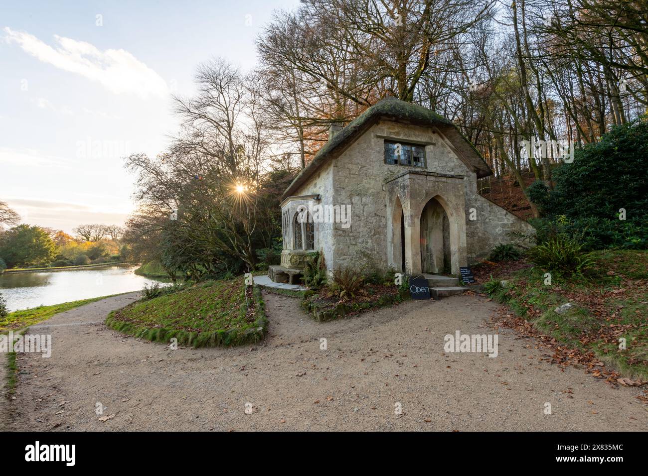 The sun setting behind the Gothic Cottage at Stourhead Gardens in ...