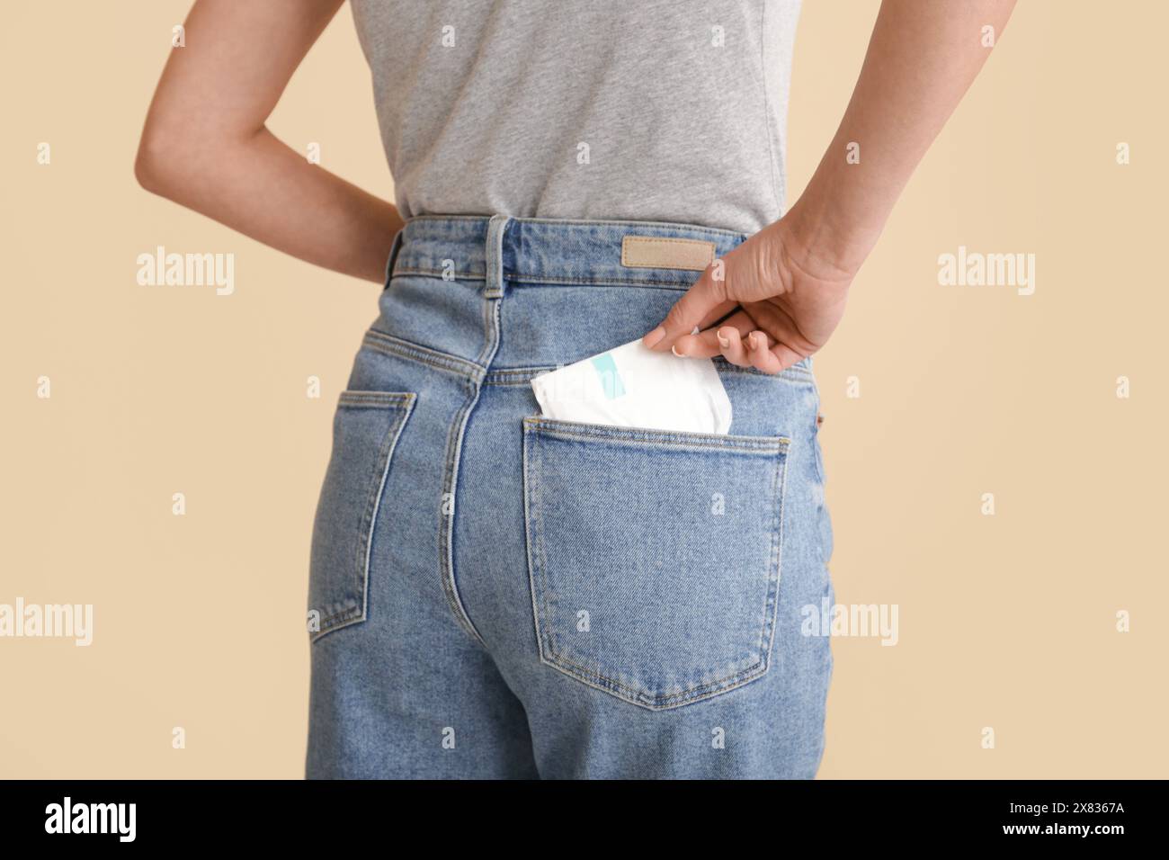 Woman putting menstrual pad into pocket on beige background Stock Photo ...