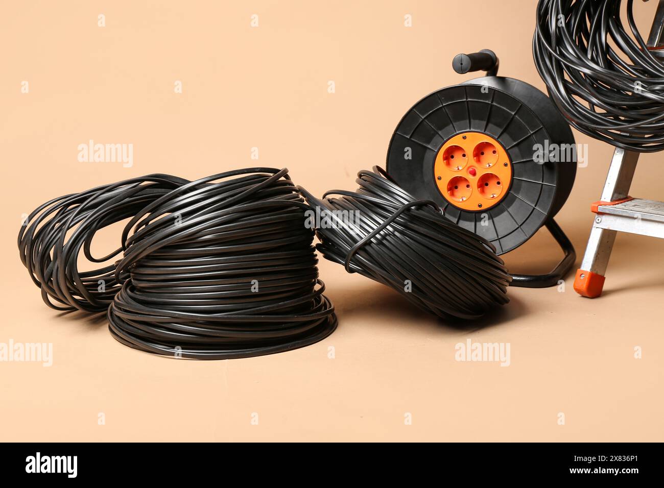 Rolled wires and extension cable reel on beige background Stock Photo ...