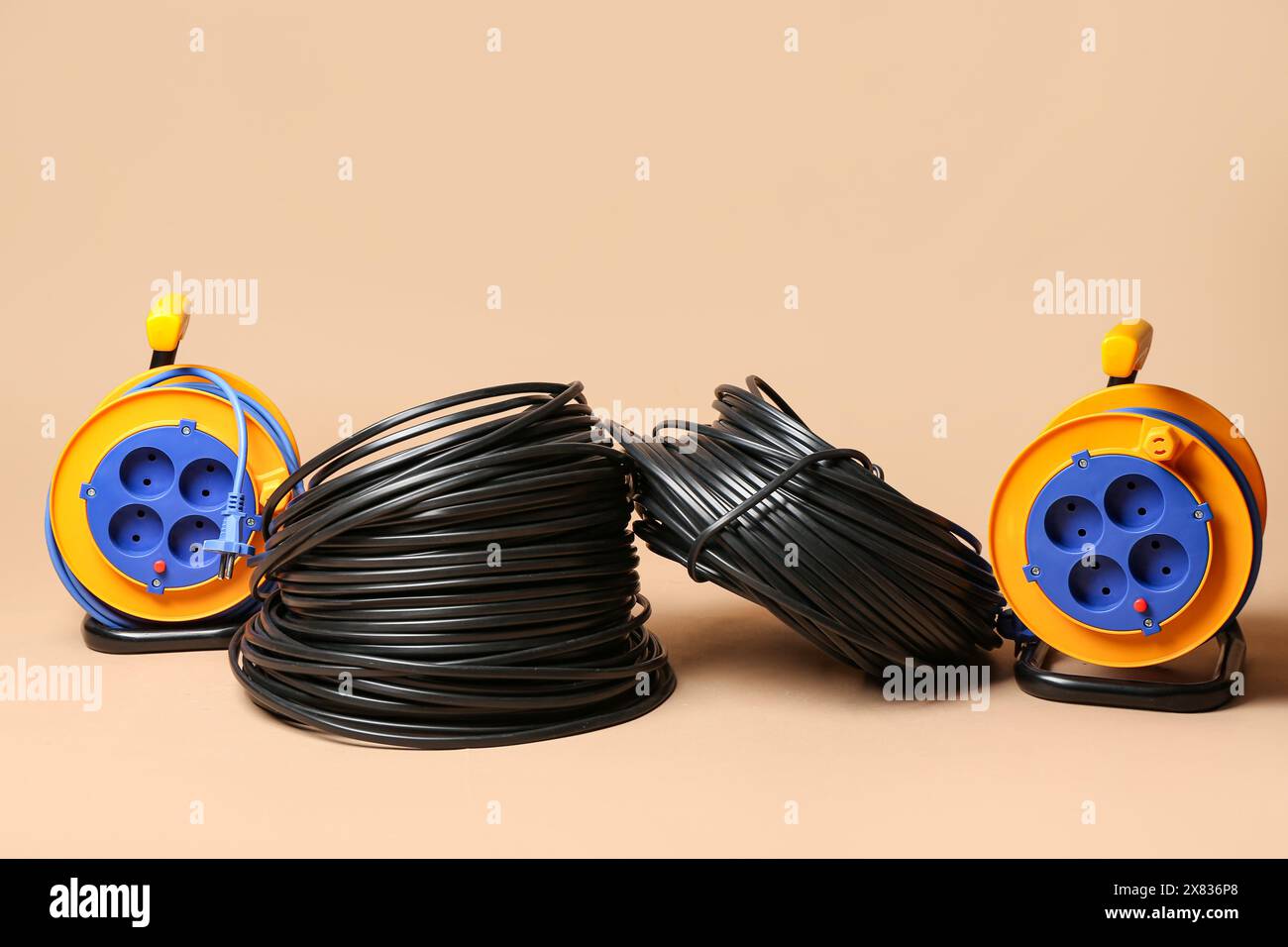 Rolled wires and extension cable reels on beige background Stock Photo ...