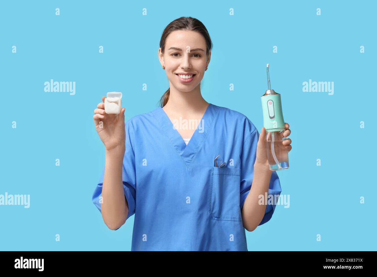 Female dentist with oral irrigator and dental floss on blue background ...