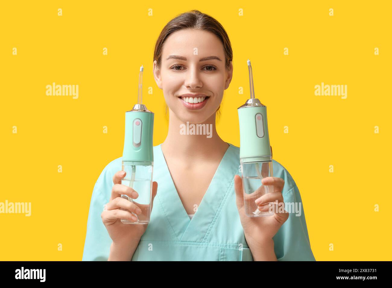 Female dentist with oral irrigators on yellow background Stock Photo ...