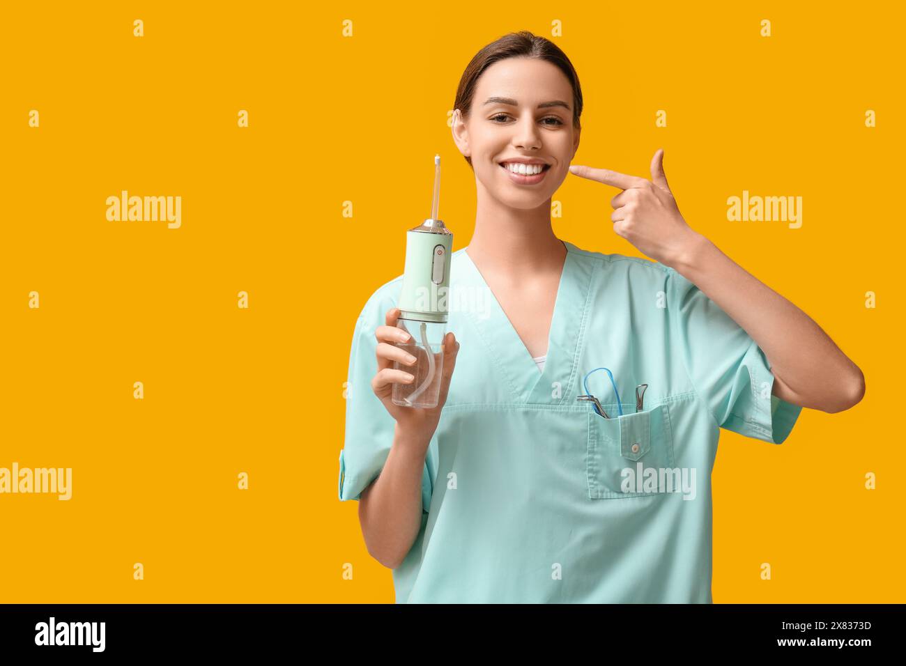 Female dentist with oral irrigator on yellow background Stock Photo - Alamy