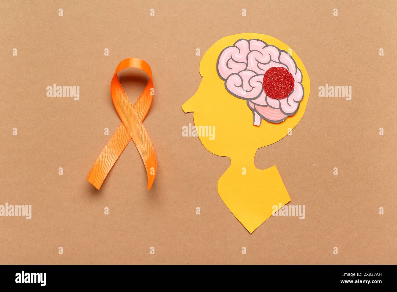 Paper human head with brain and orange ribbon on brown background ...
