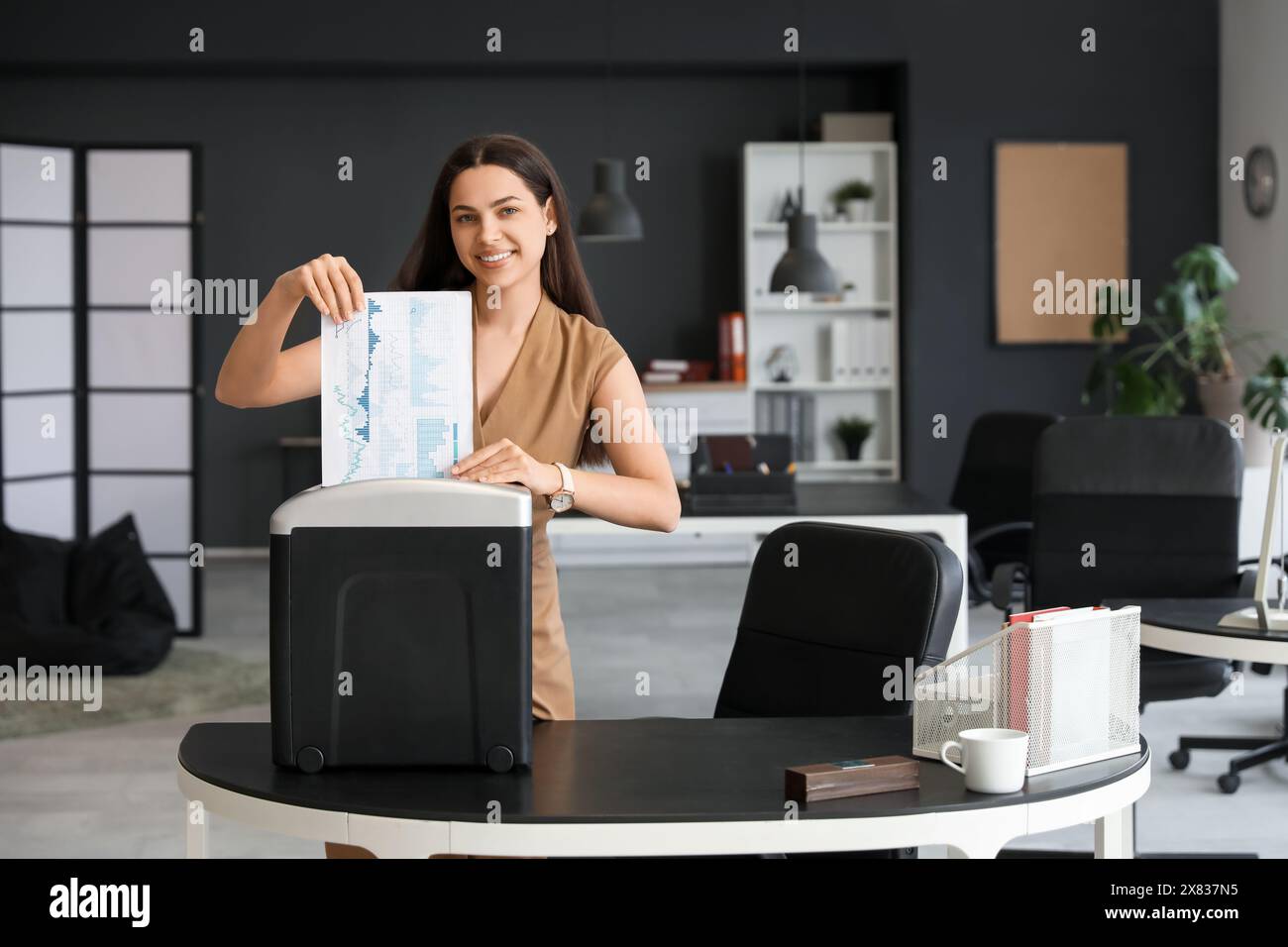 Young secretary destroying documents using shredder in office Stock ...