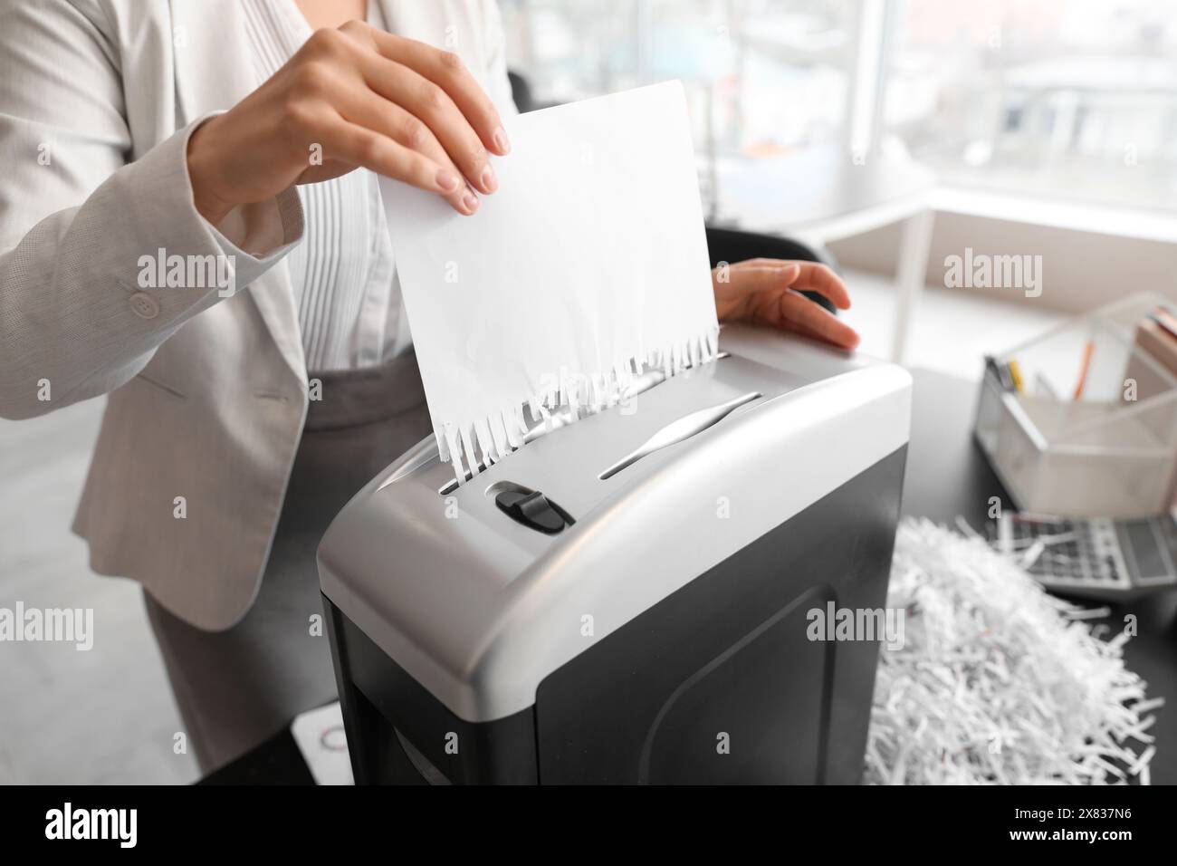 Young secretary destroying paper sheet using shredder in office ...