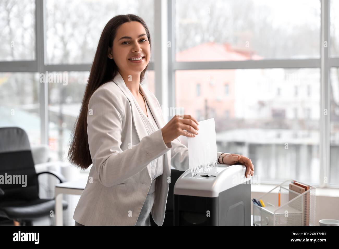 Young secretary destroying paper sheet using shredder in office Stock ...