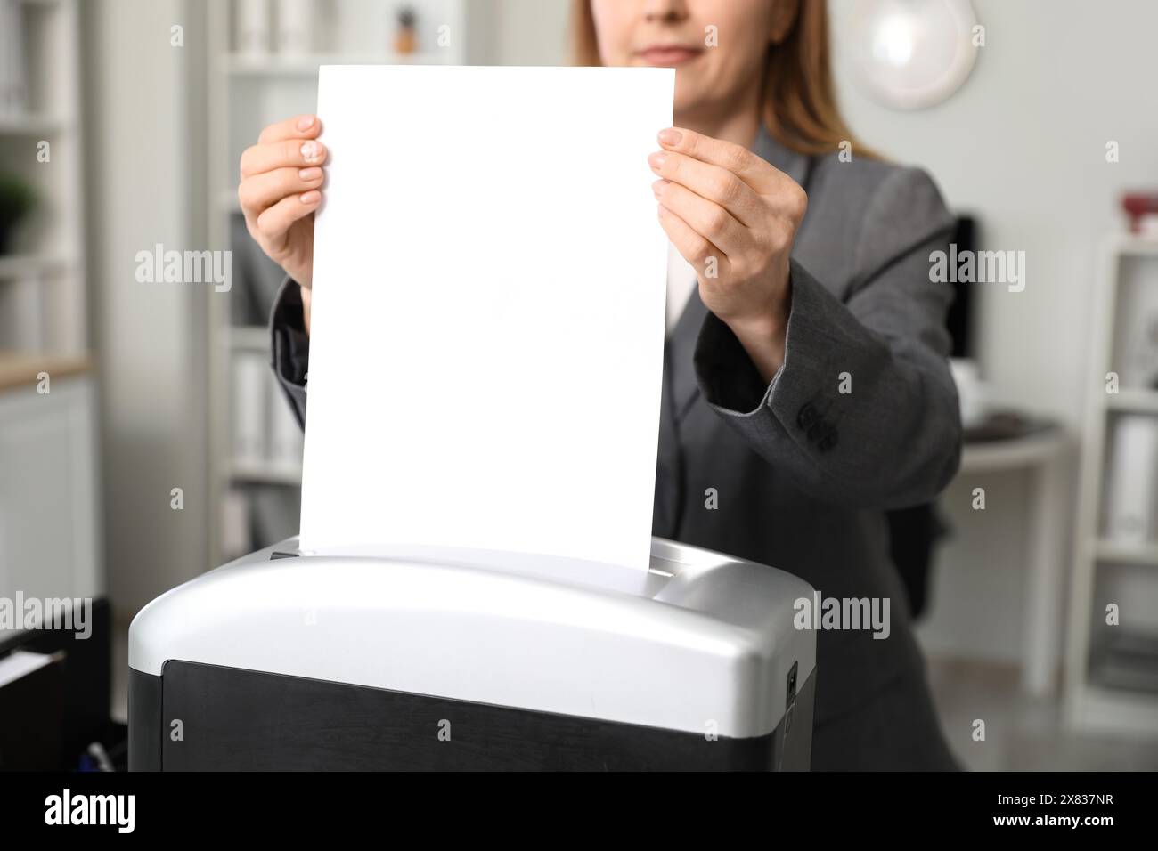 Adult secretary destroying paper sheet using shredder in office ...