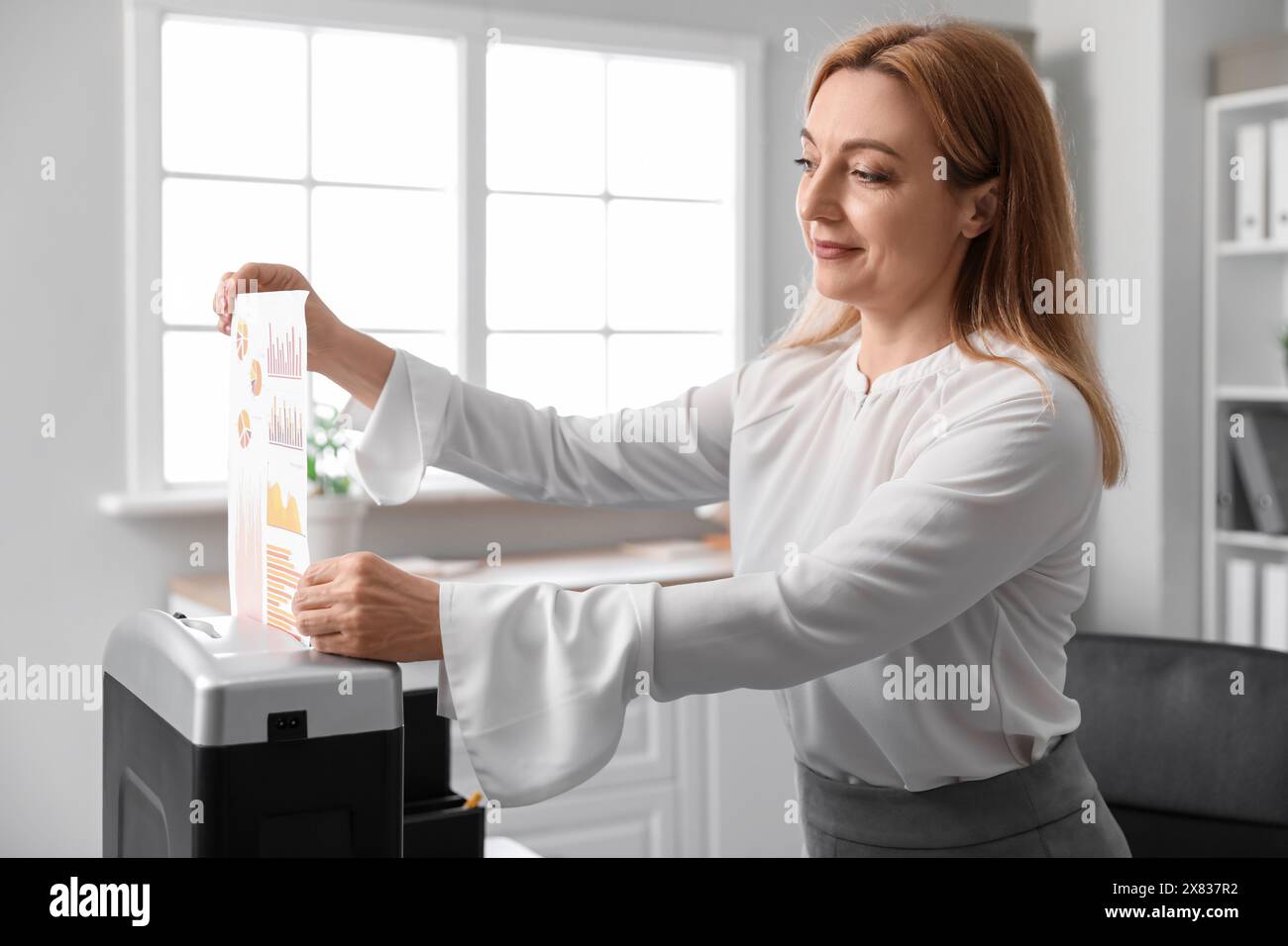 Adult secretary destroying documents using shredder in office Stock ...