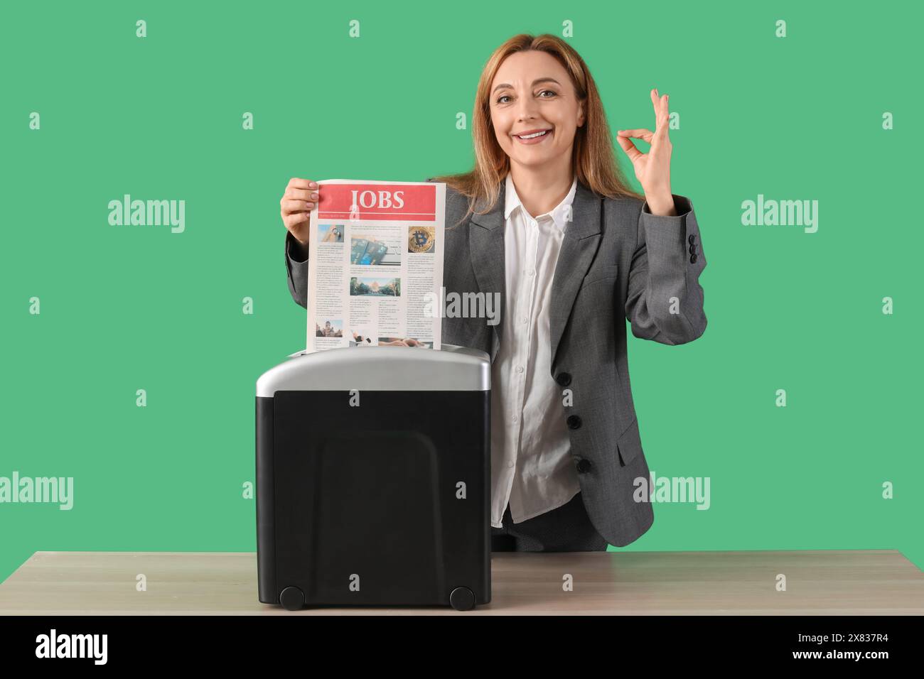 Adult woman showing OK gesture and destroying newspaper using shredder ...