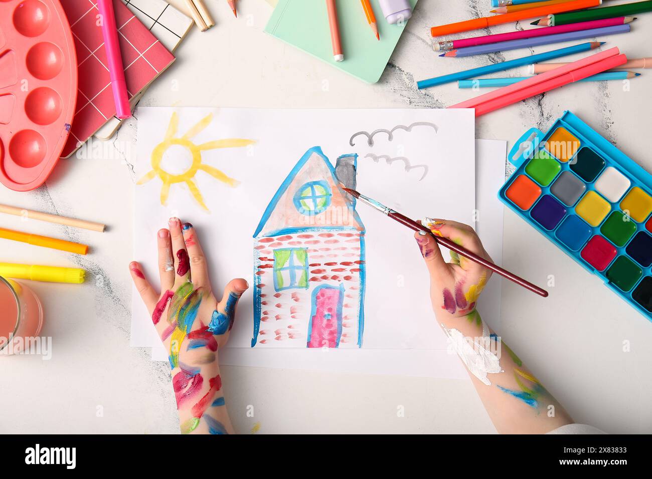 Child's hand drawing home with brush, watercolor paints and different ...