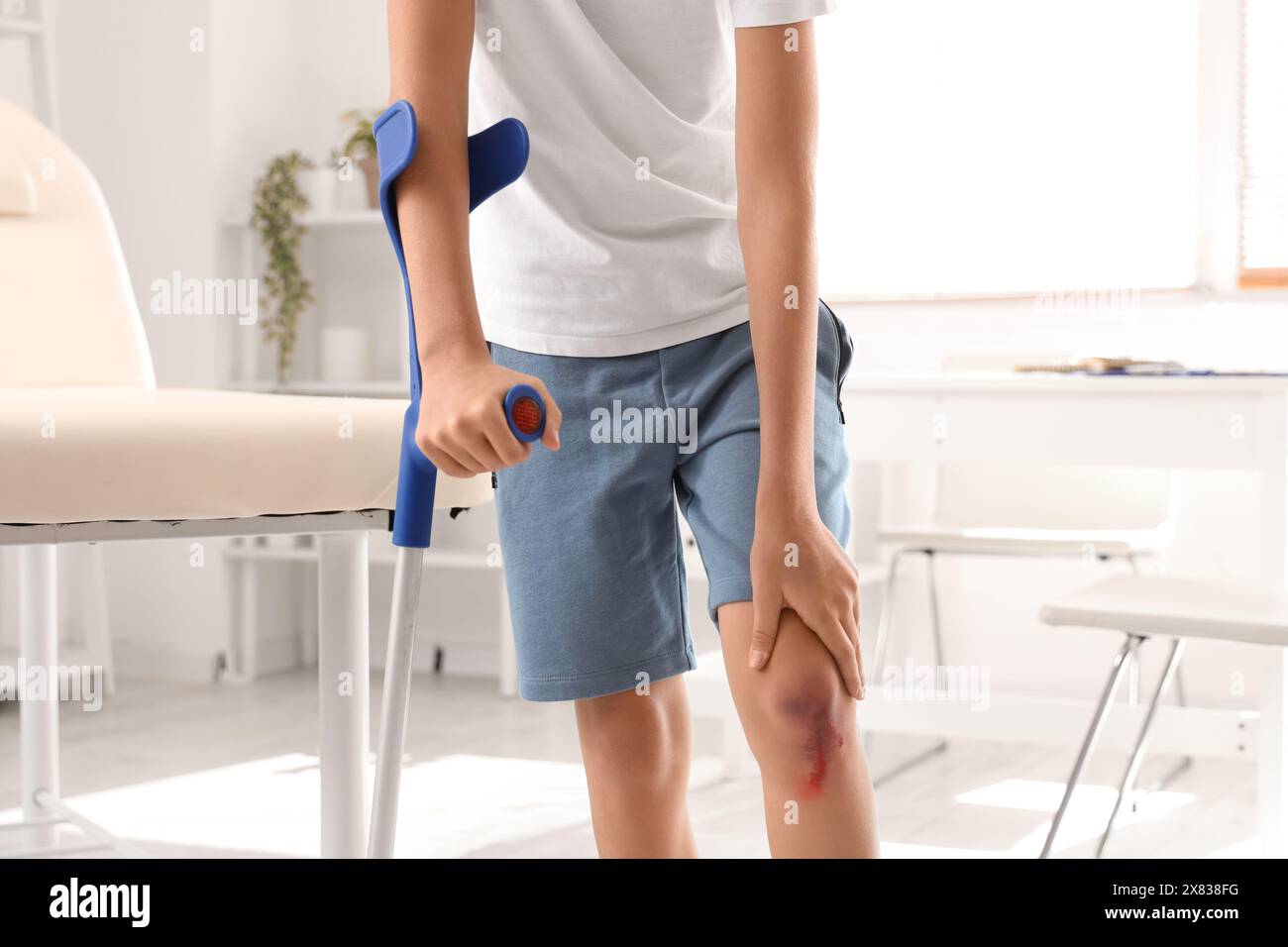 Little boy with injured knee and crutch in clinic, closeup Stock Photo ...
