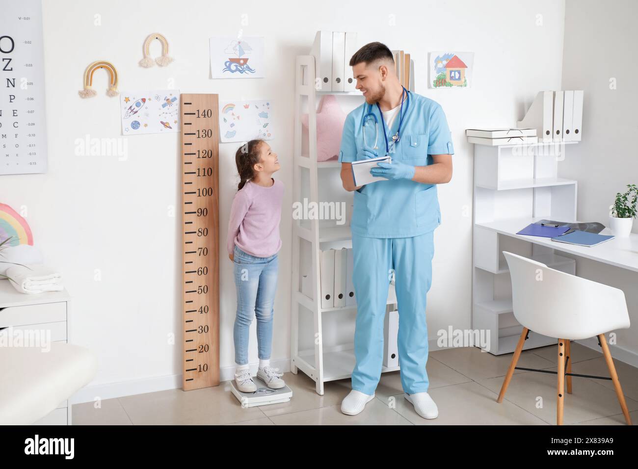 Male pediatrician measuring little girl's weight in clinic Stock Photo ...