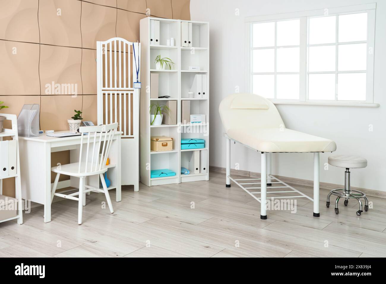 Interior of medical office with couch, doctor's workplace and shelf ...