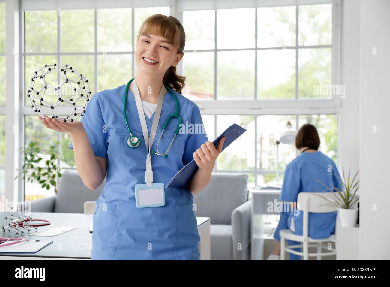 Female medical intern with clipboard and molecular model in clinic ...