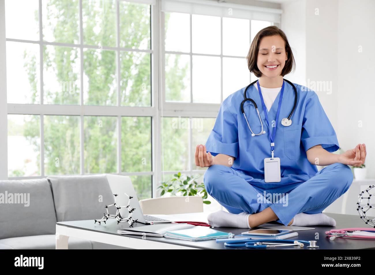 Female medical intern meditating on table in clinic Stock Photo - Alamy
