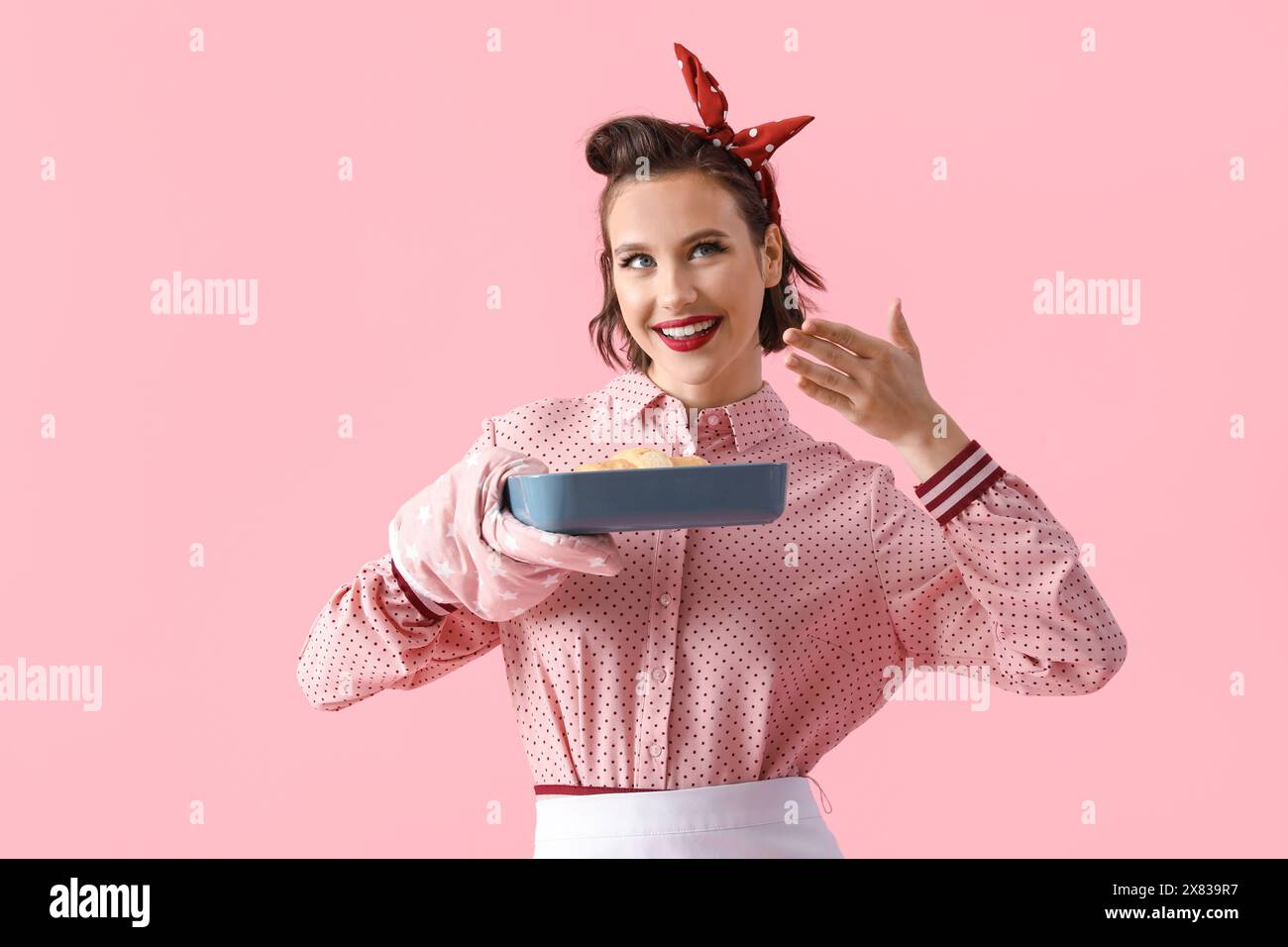 Beautiful young happy pin-up housewife holding baking tray with ...