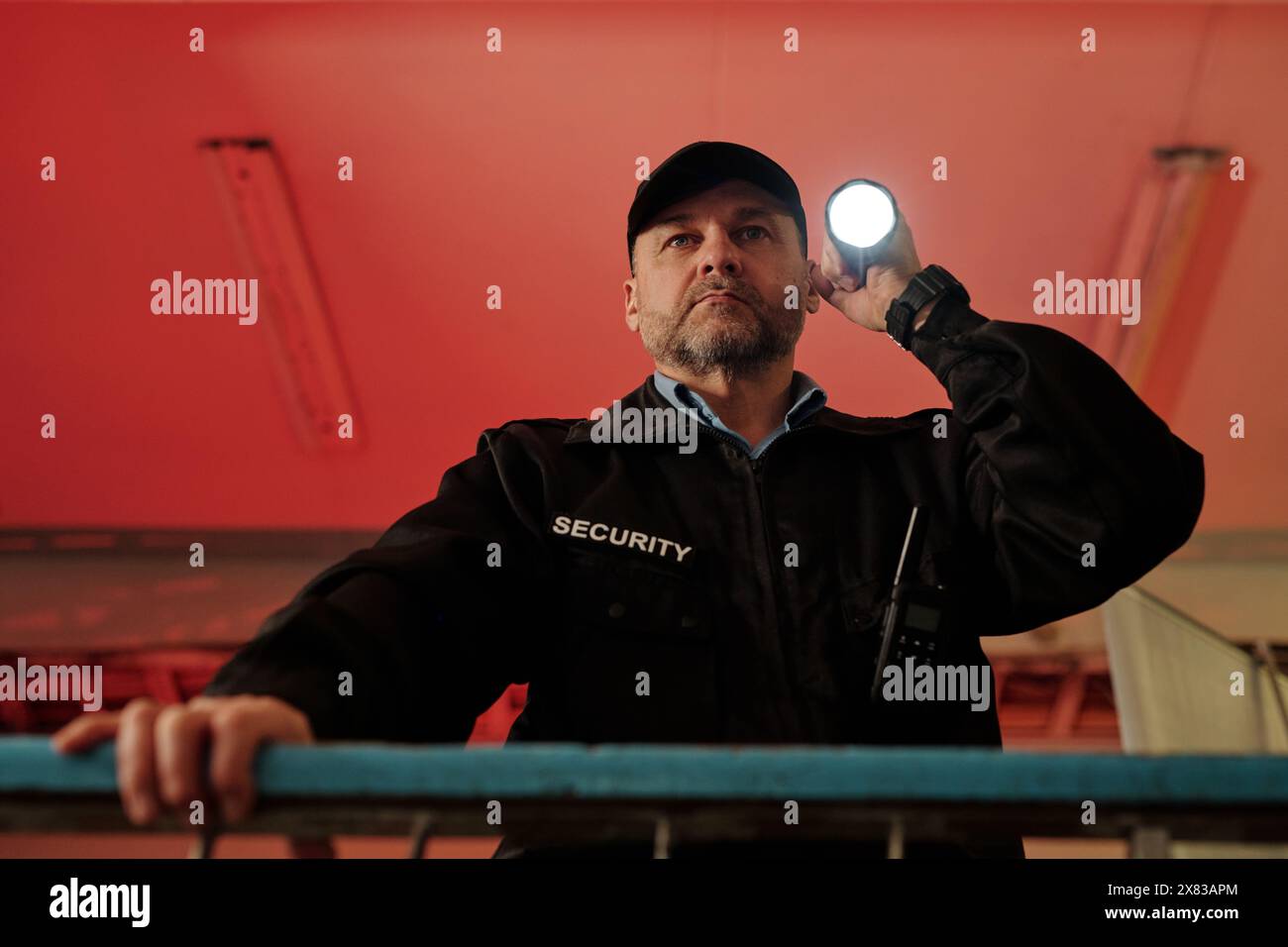 Below view of serious male security guard in uniform lighting forward ...