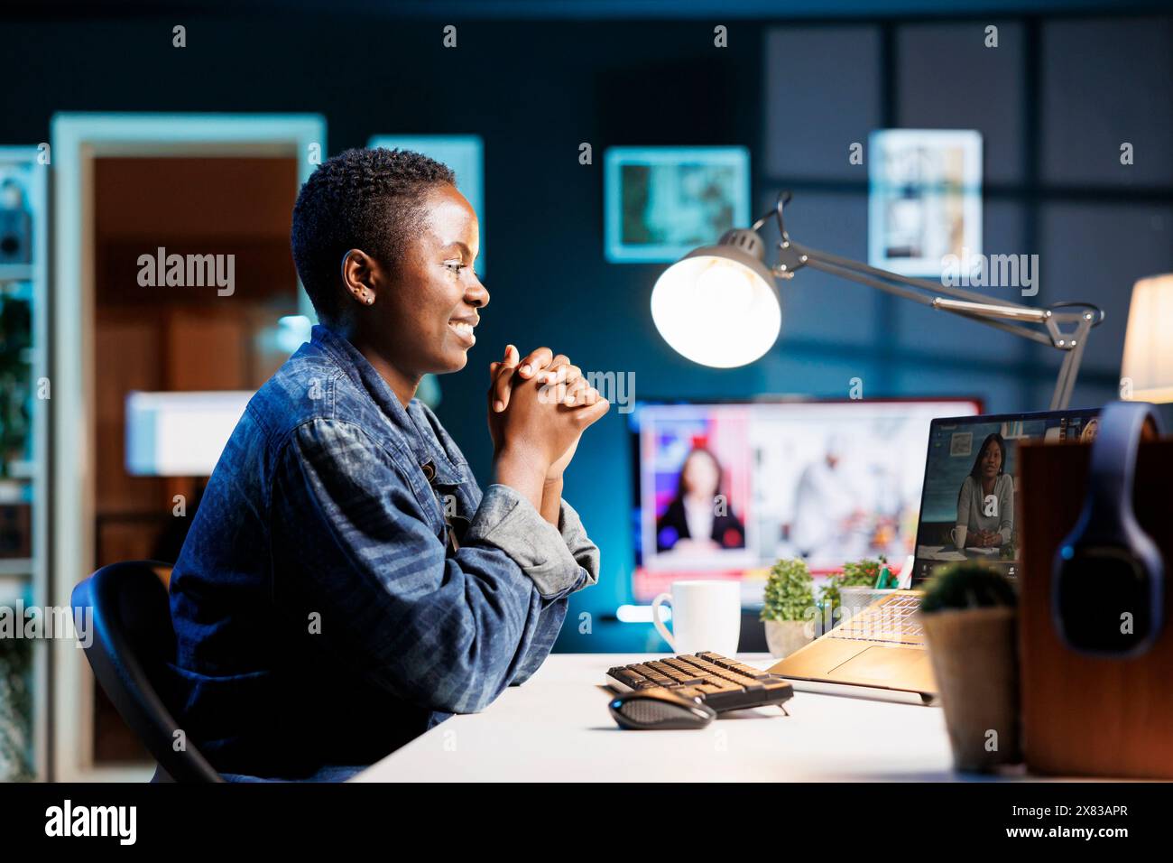 African american freelancer with laptop is attending an online meeting in a living room. Smiling ...