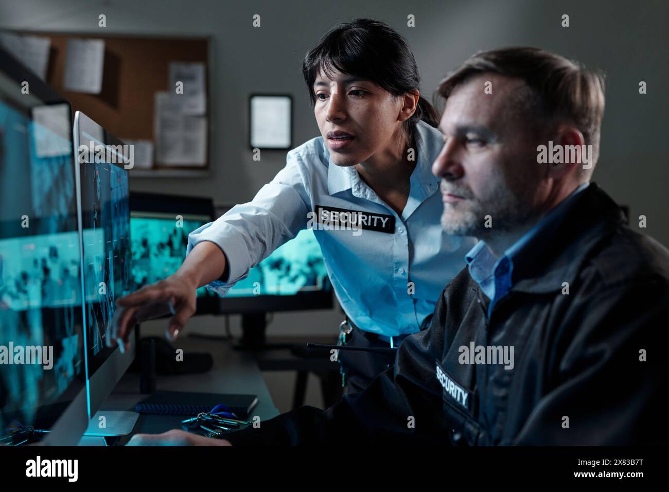 Young Hispanic female security guard in uniform standing next to male ...