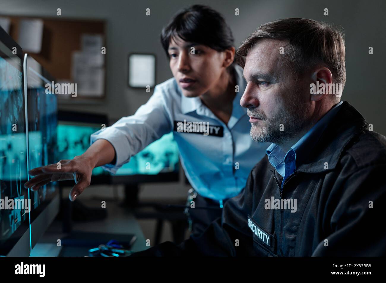 Serious mature security guard looking at computer screen while his ...