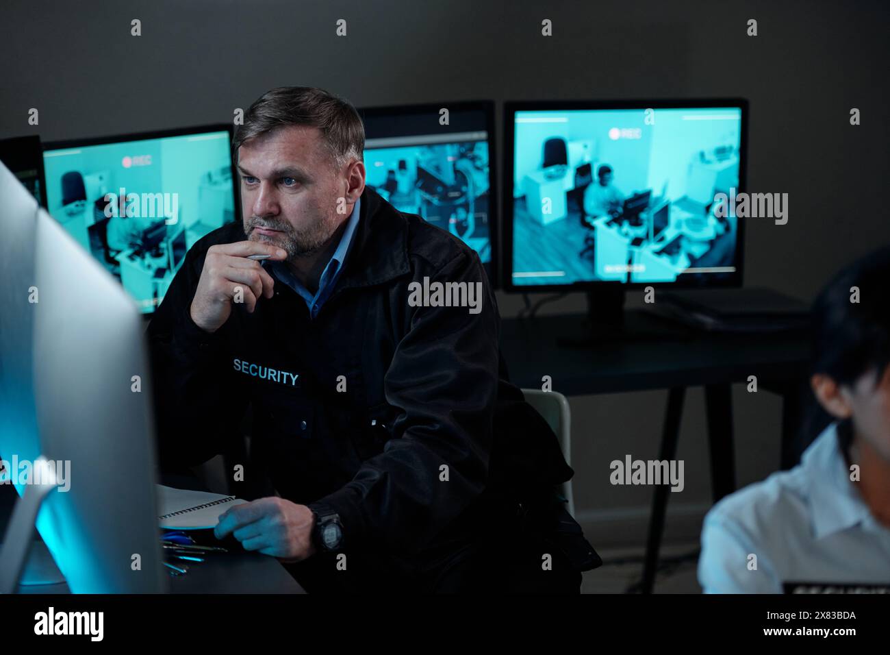 Mature male security guard concentrating on watching cctv video on ...