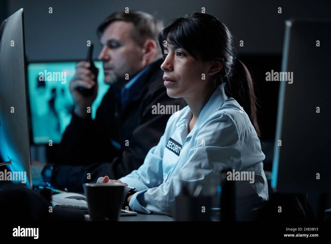 Young serious female officer from surveillance department looking at ...