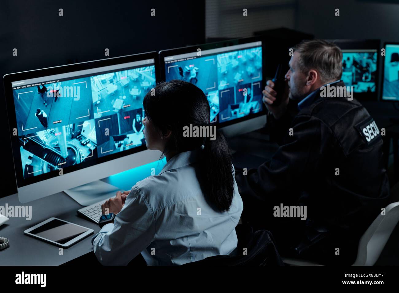 Two intercultural male and female officers in uniform sitting in front ...