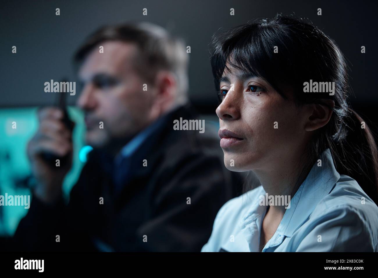 Young serious and tired female officer in uniform looking at screen of ...