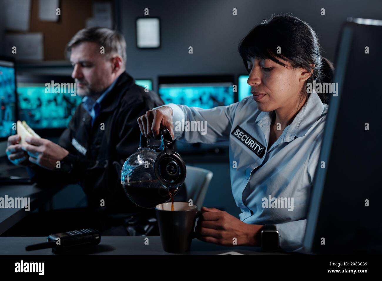 Young Hispanic female security guard with teapot pouring tea in mug ...