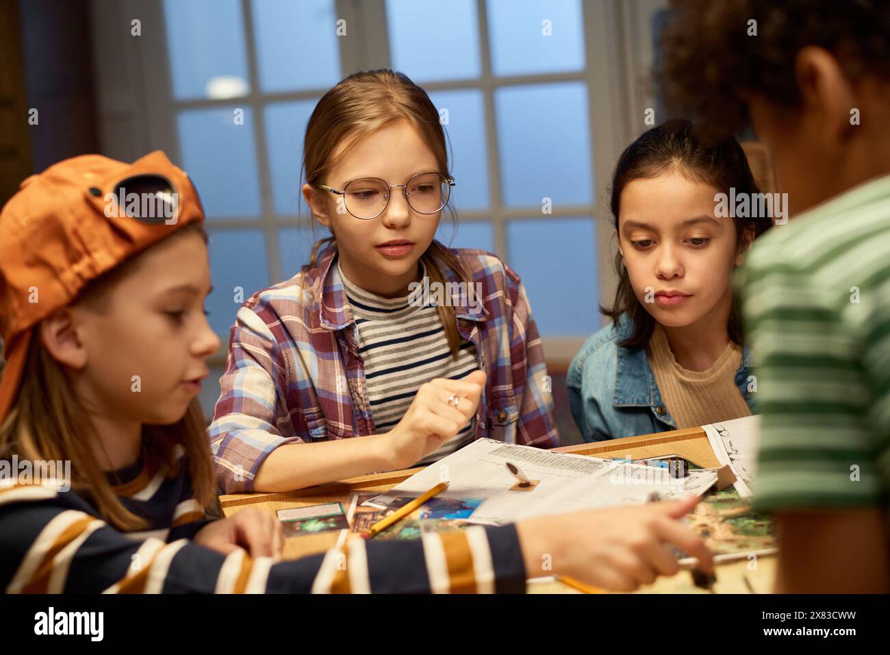 Two serious girls looking at their friend moving piece of board game ...
