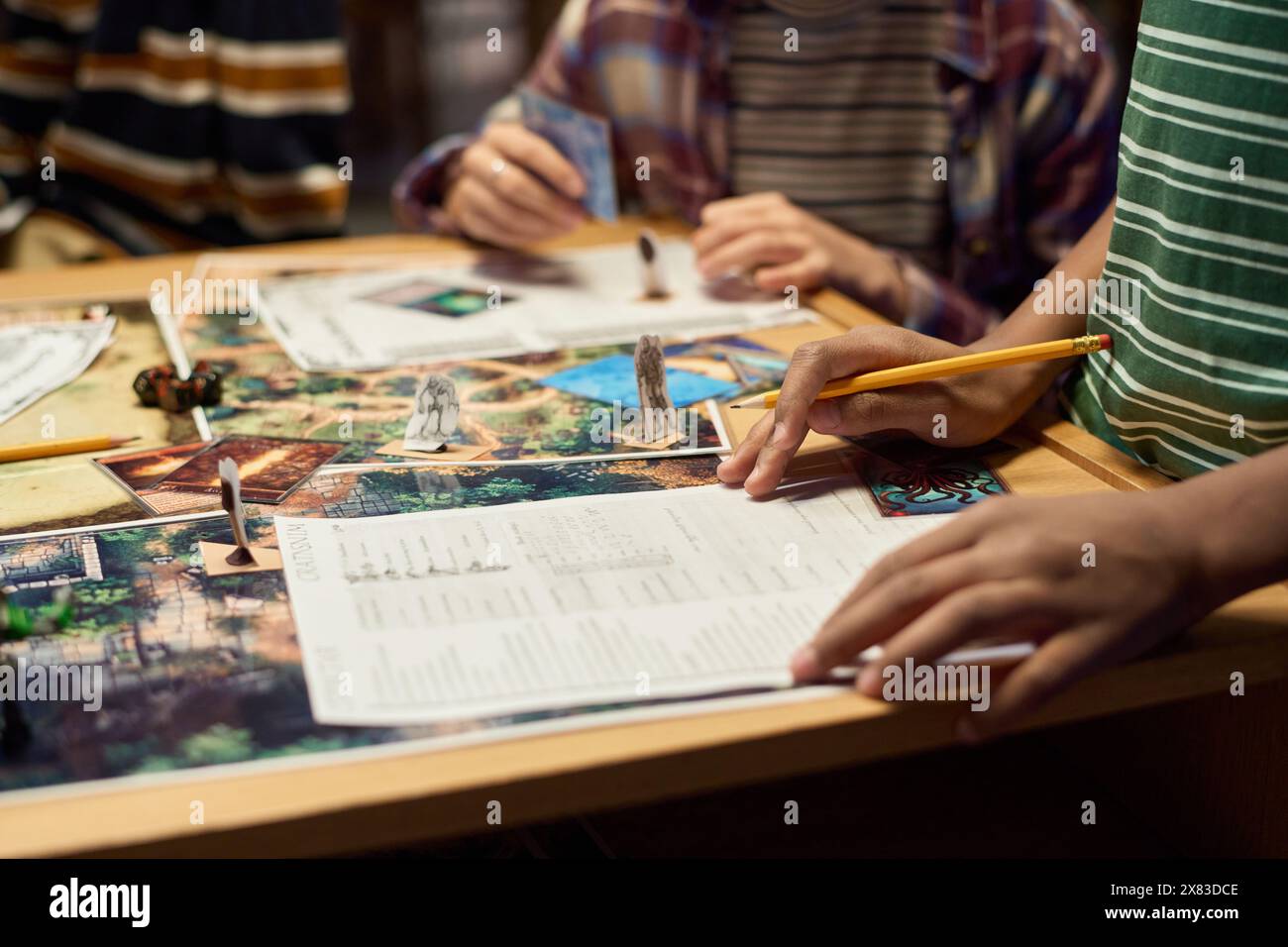 Hands of youthful African American game leader with pencil looking ...
