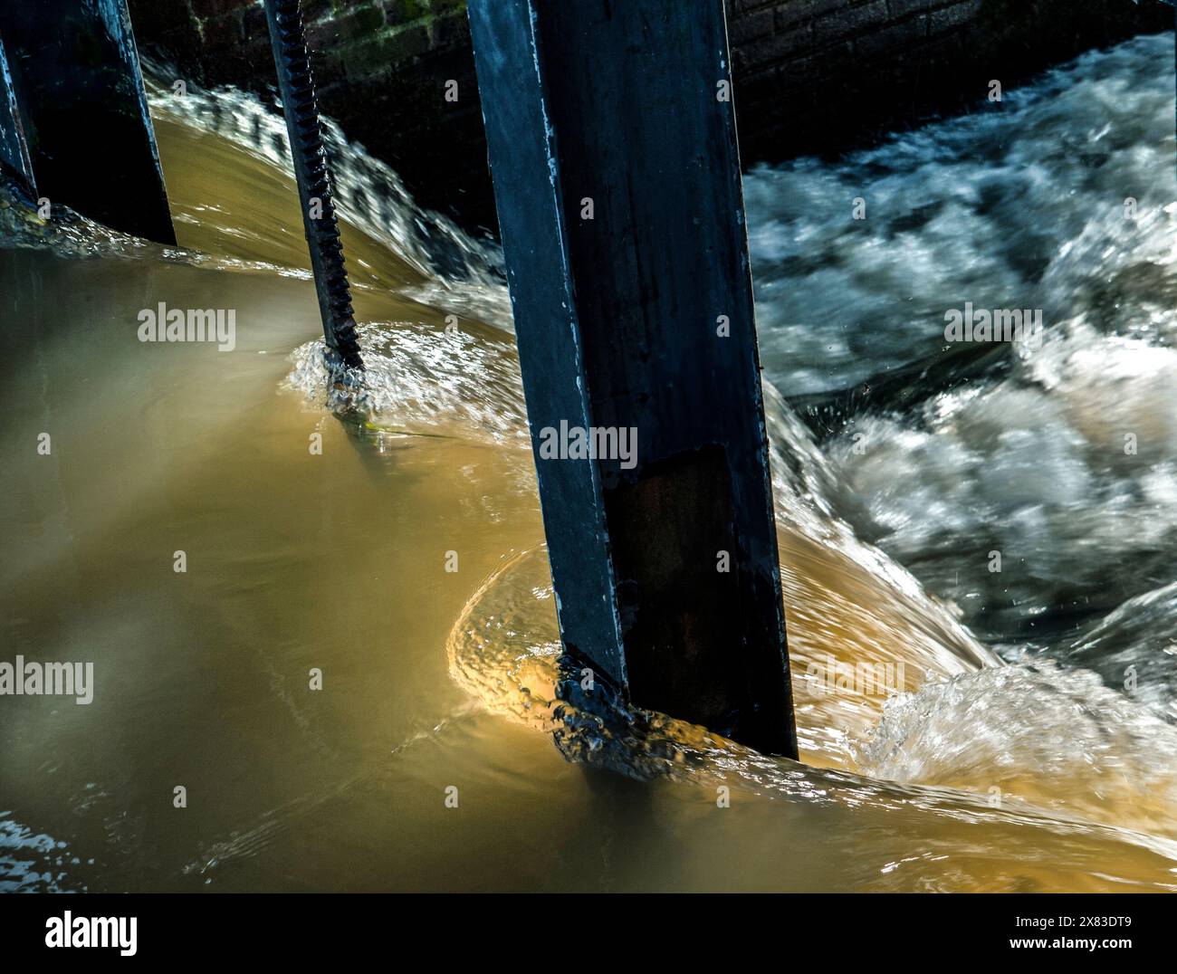 Brown Flood water runs over an open river weir after recent rainfall UK ...