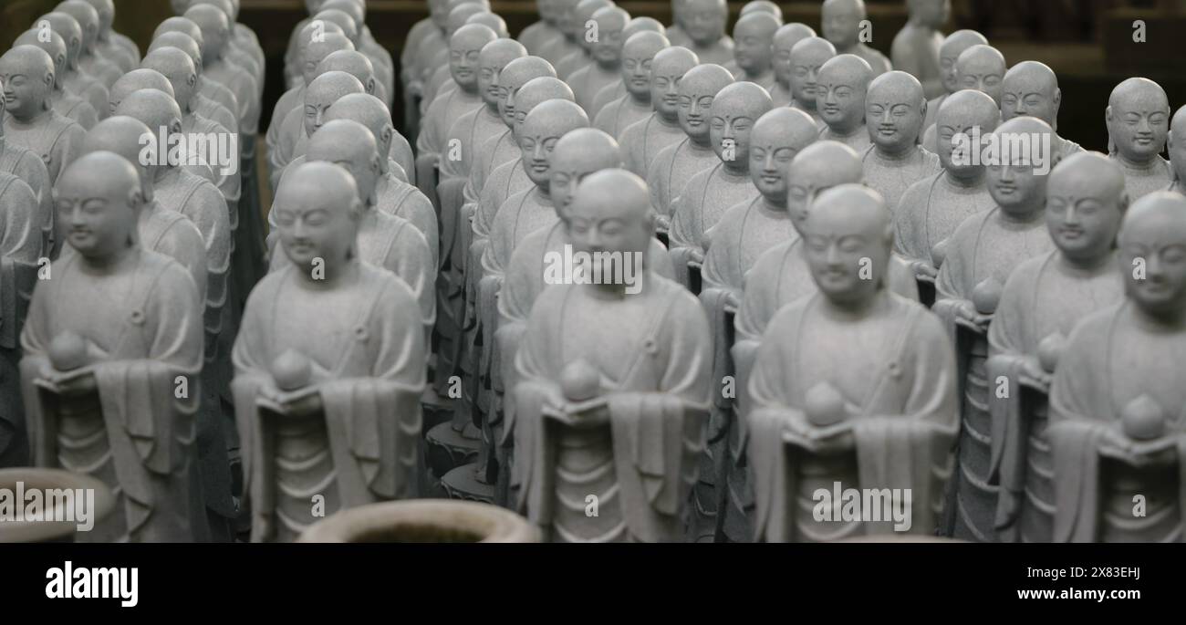 A collection of small, identical stone Buddha statues arranged in rows ...