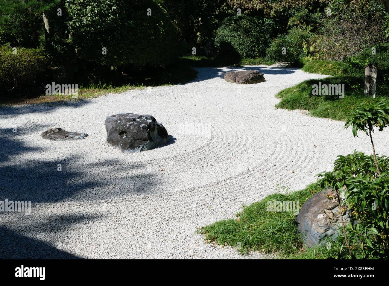 A serene Japanese Zen garden with raked white gravel, large rocks, and ...