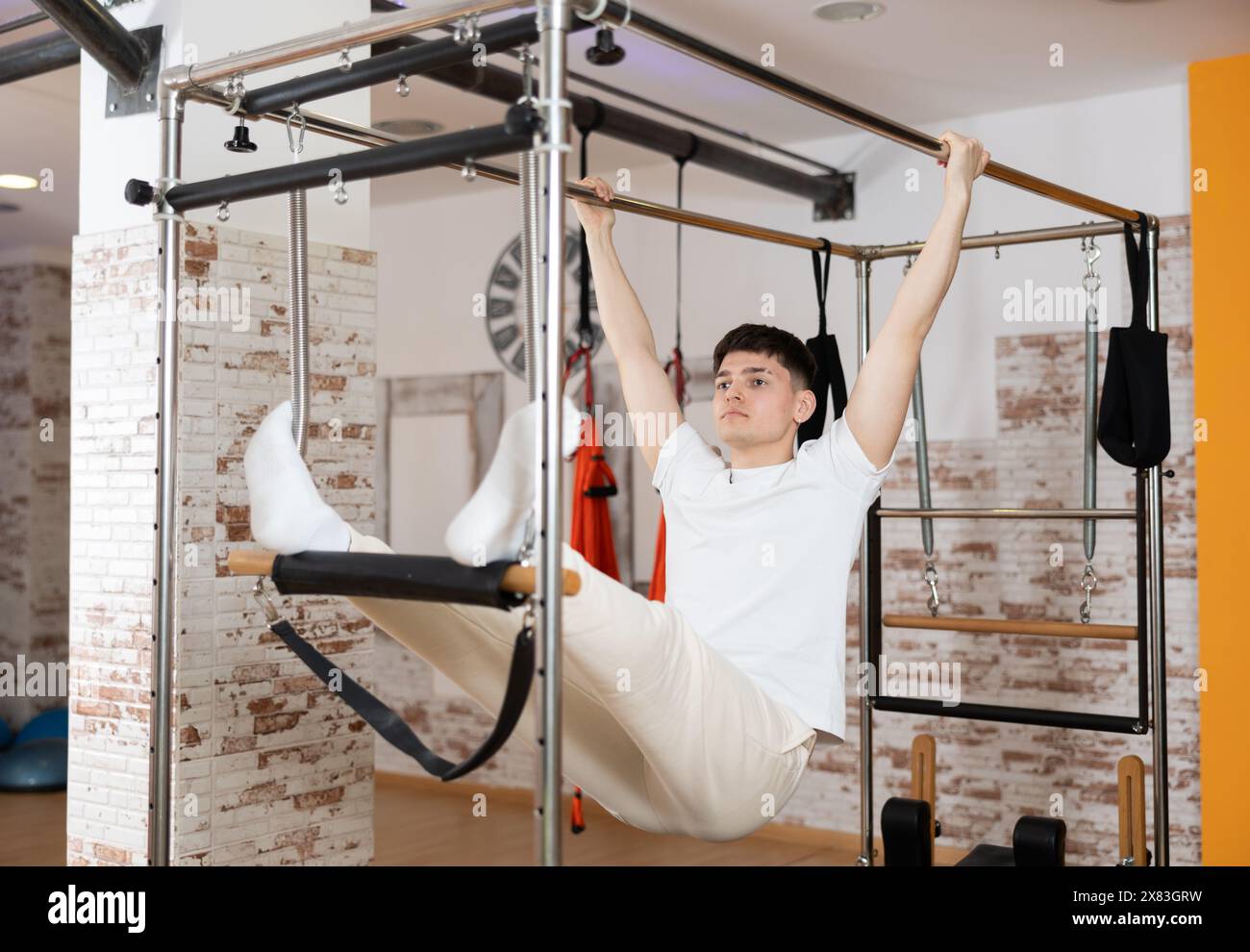 Guy performing hanging exercise on trapeze table in Pilates studio ...