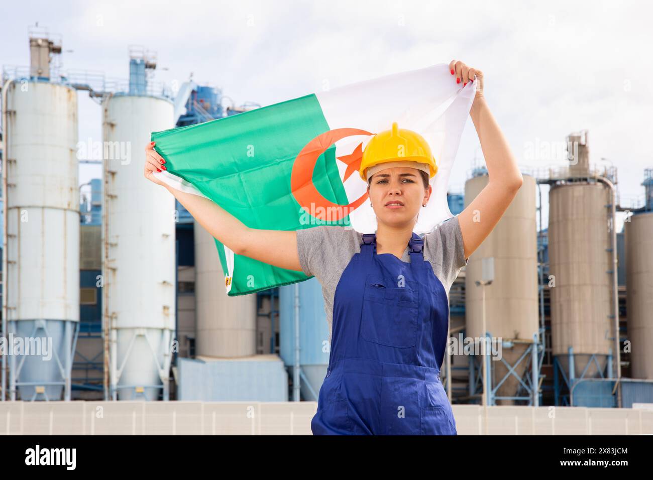 Upset disappointed young female engineer in helmet waving state flag of ...