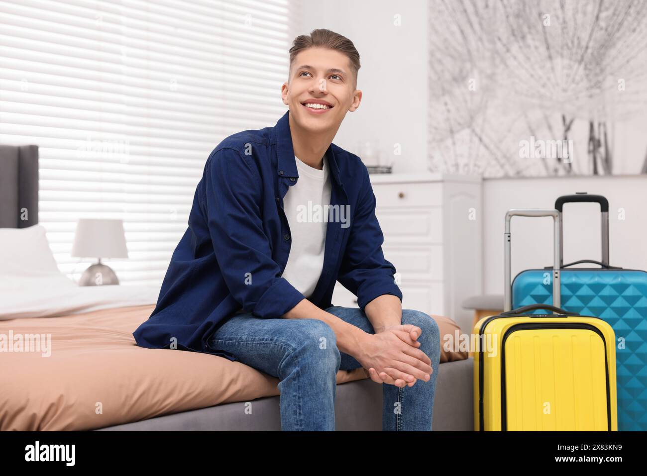 Smiling guest relaxing on bed in stylish hotel room Stock Photo - Alamy