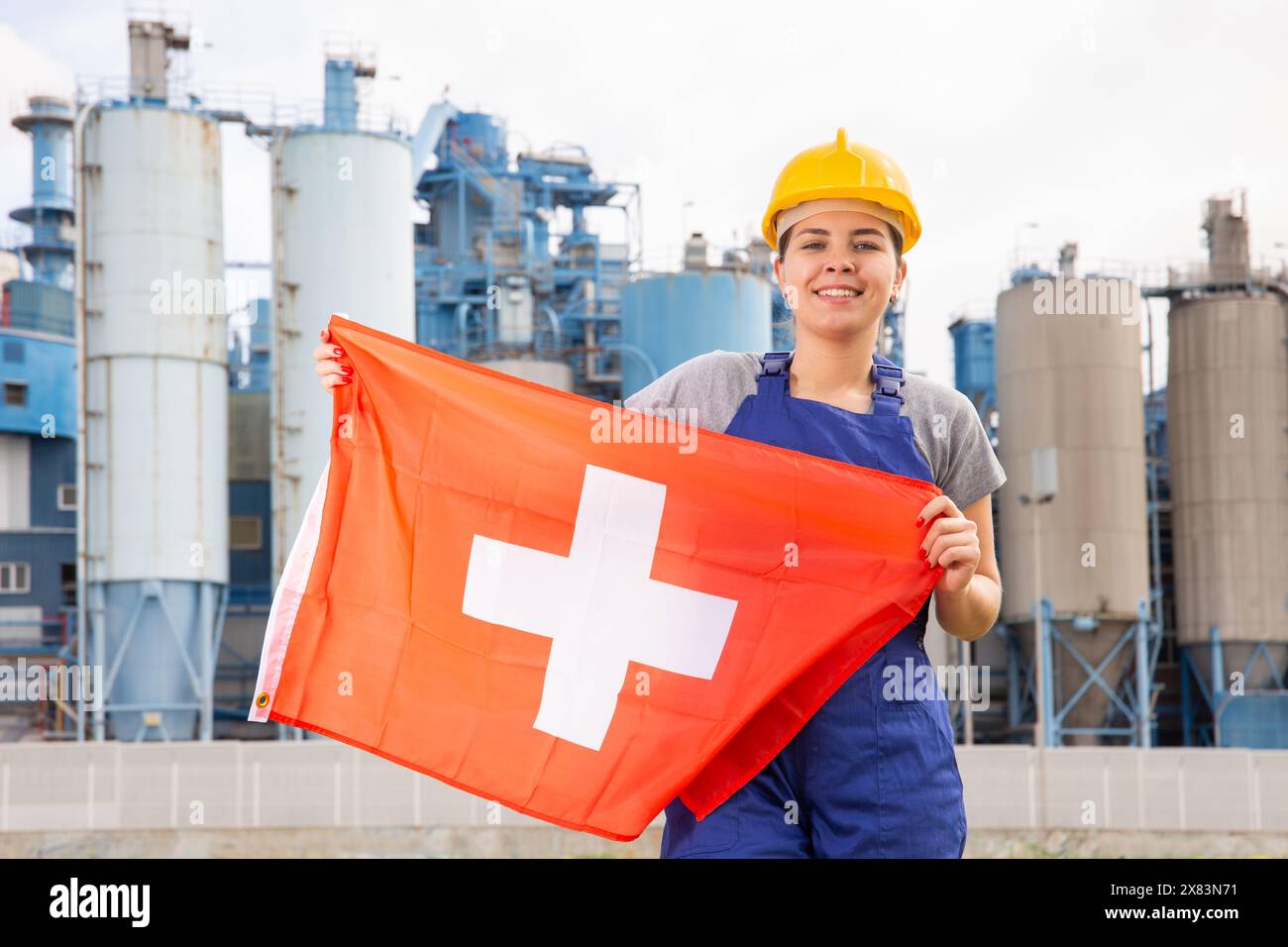 Young female engineer in helmet waving state flag of Switzerland while ...