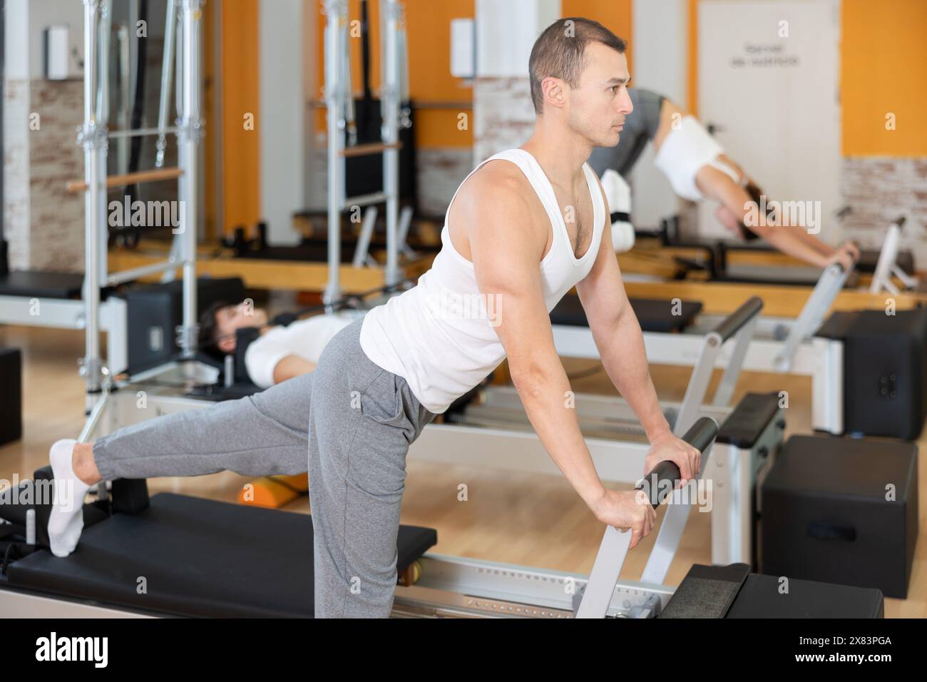 Man works out in gym and performs set of exercises to stretch leg ...
