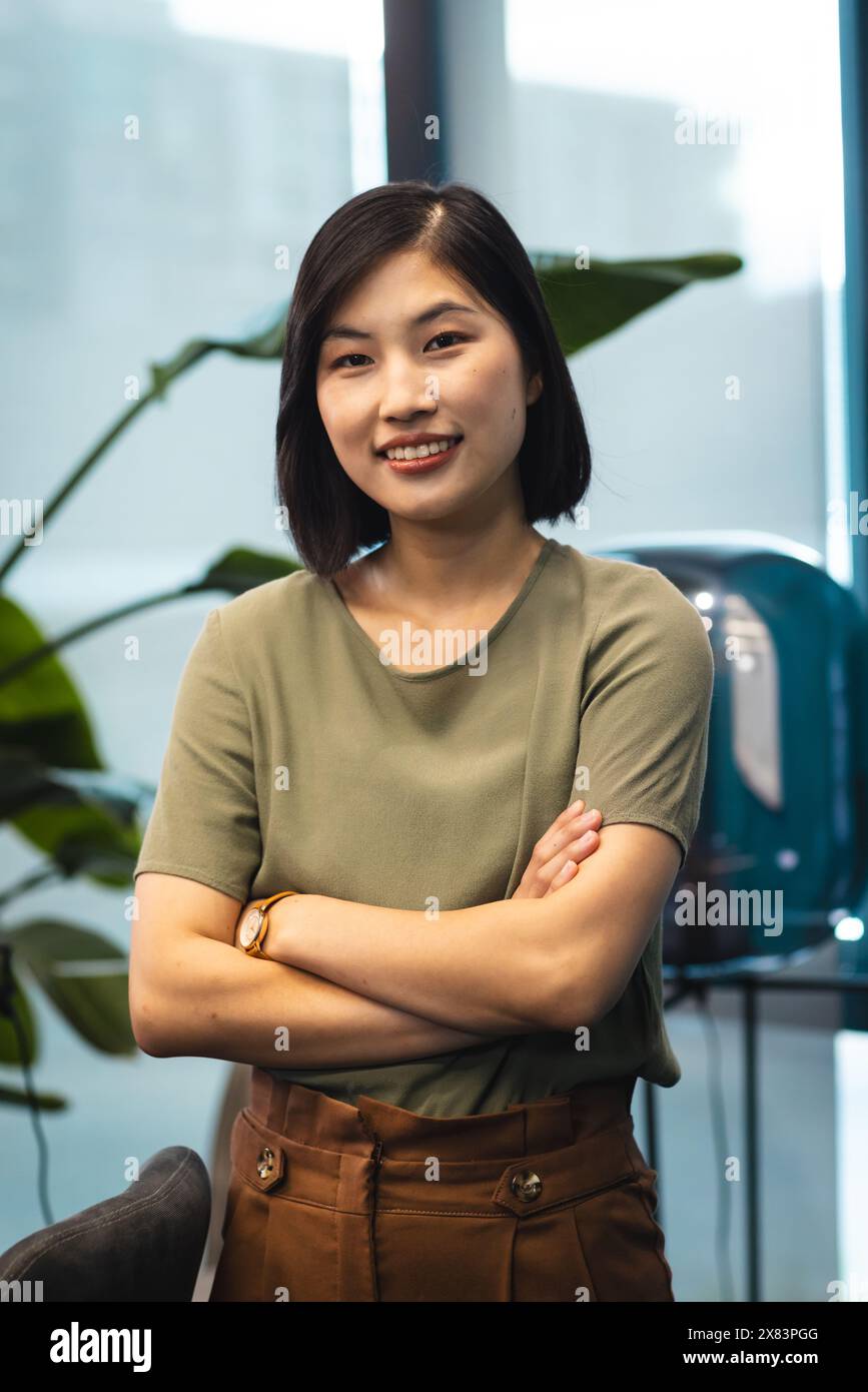 At modern office for business, young Asian woman standing with arms ...