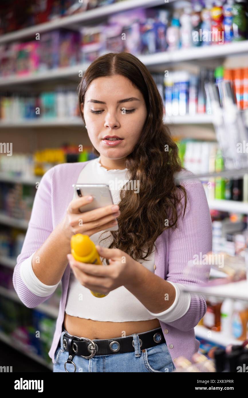 Female shopper scanning a QR code using a mobile phone in cosmetics ...