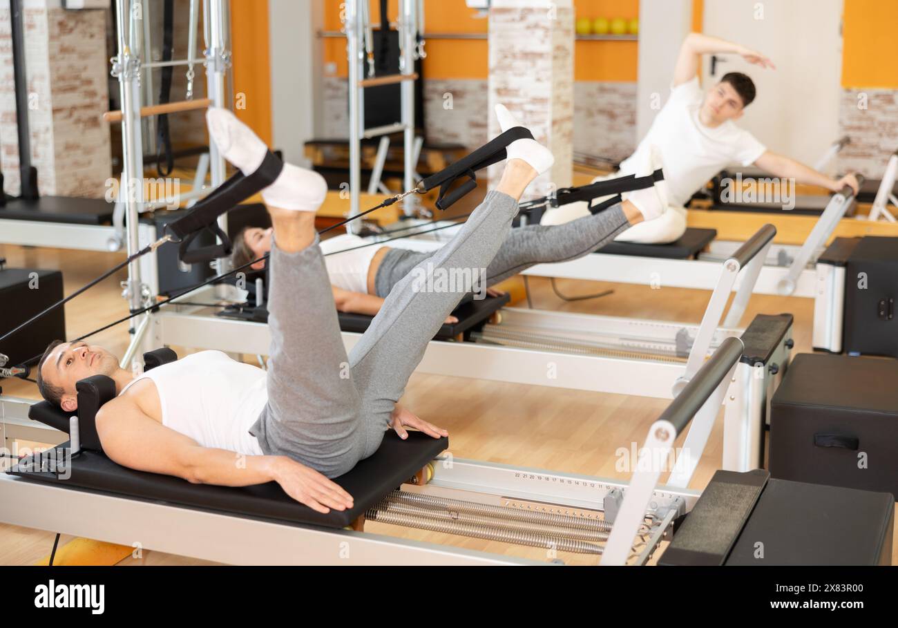 Man works out in gym and performs set of exercises to stretch leg ...