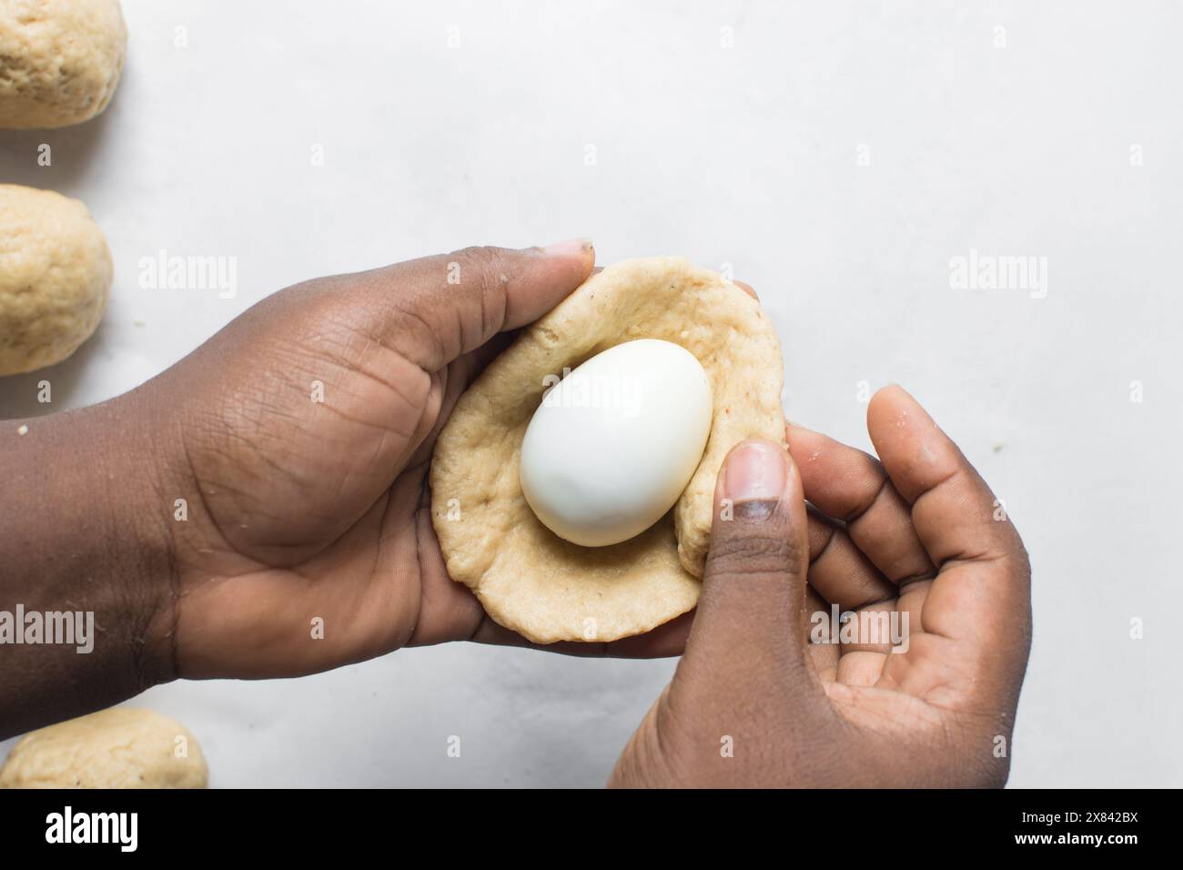 Egg being wrapped in dough to make nigerian egg roll, process of making ...