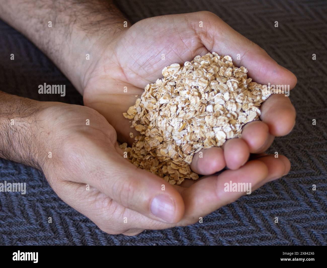 Close up picture of hands of a young man rolled oats falling from one ...
