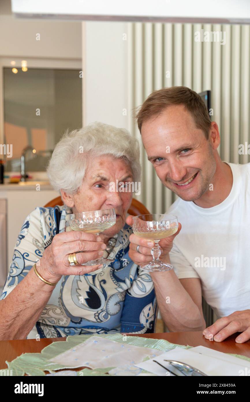 attractive elderly lady with a glass sparkling wine drinks a toast to ...