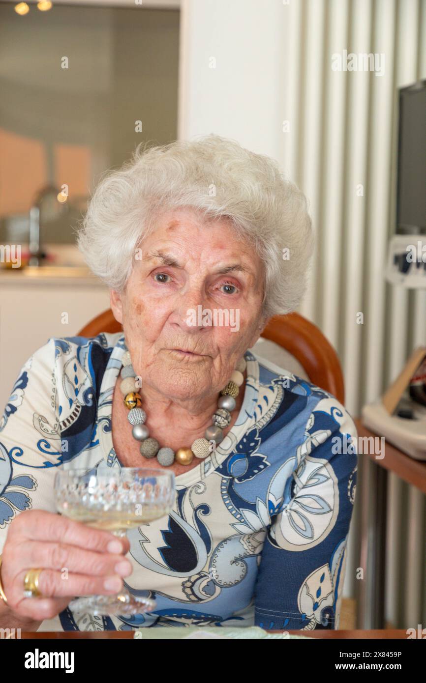 attractive elderly lady with a glass sparkling wine drinks a toast to ...