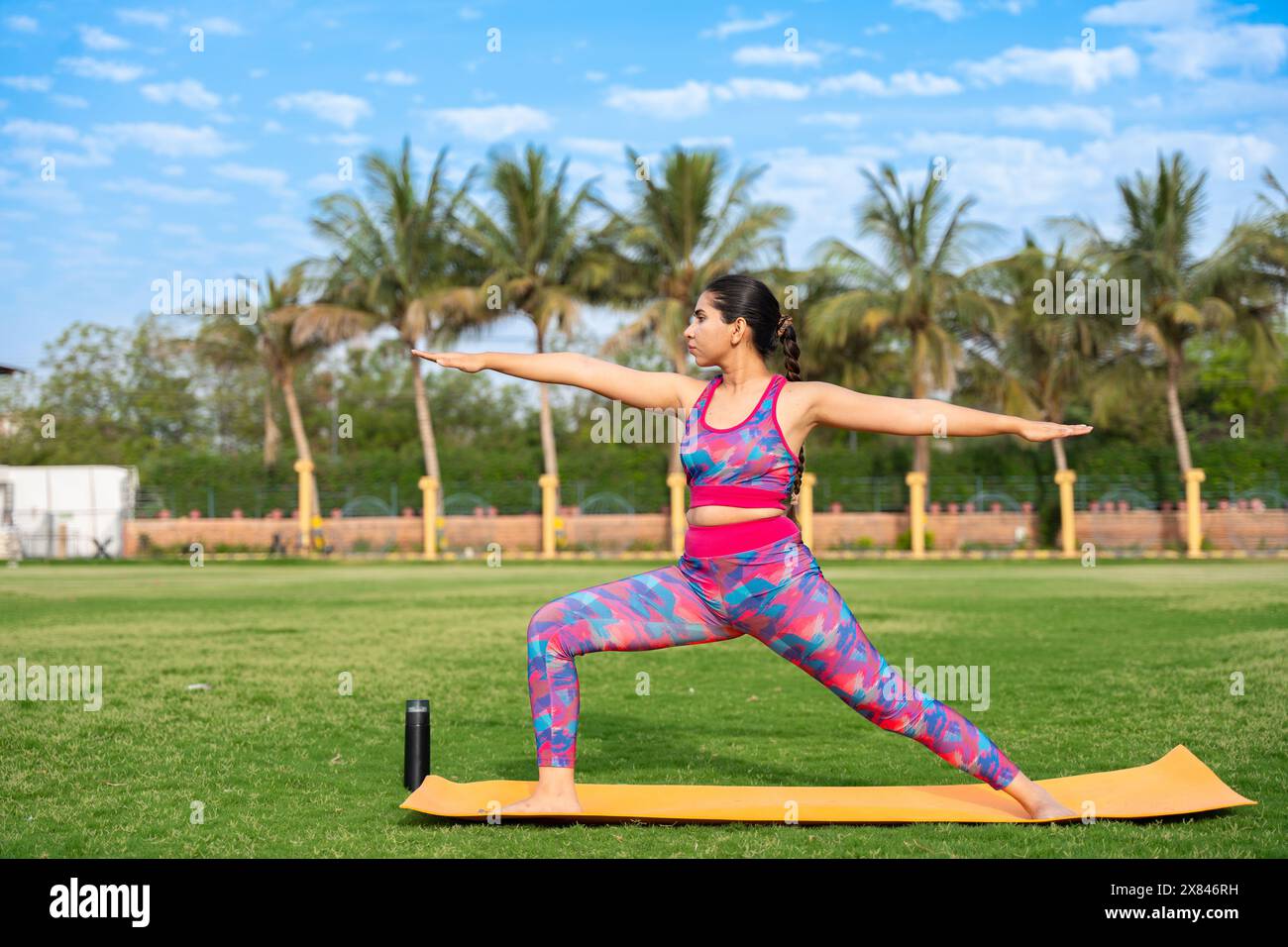 Sporty young indian woman doing warrior yoga pose in garden. exercise ...