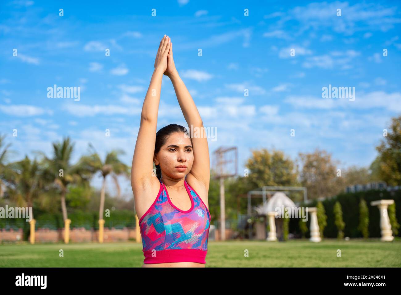 young indian woman practicing surya namaskar yoga pose in garden ...